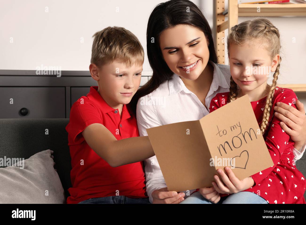 Happy woman receiving greeting card from her children at home Stock ...