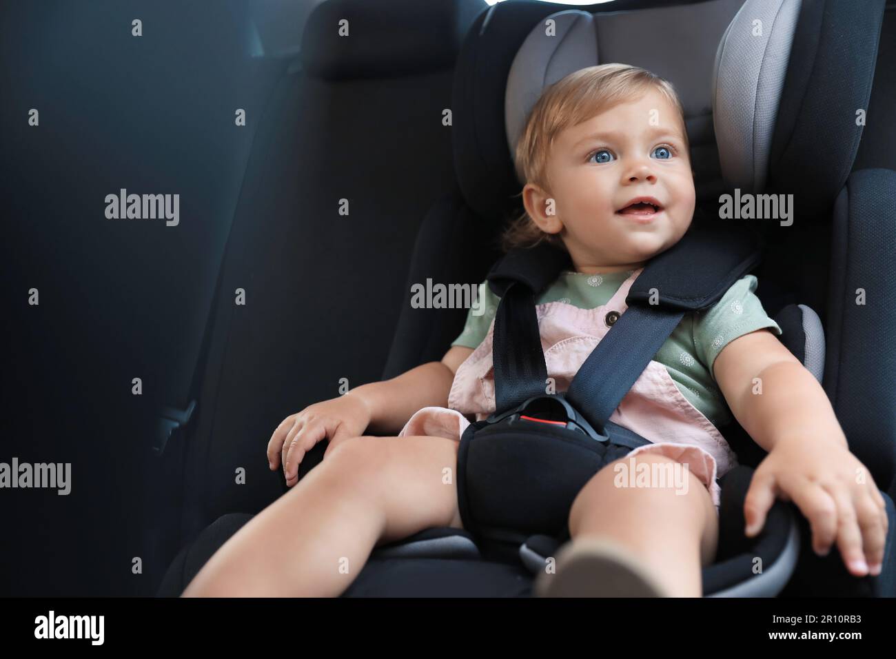 Cute little girl sitting in child safety seat inside car Stock Photo ...