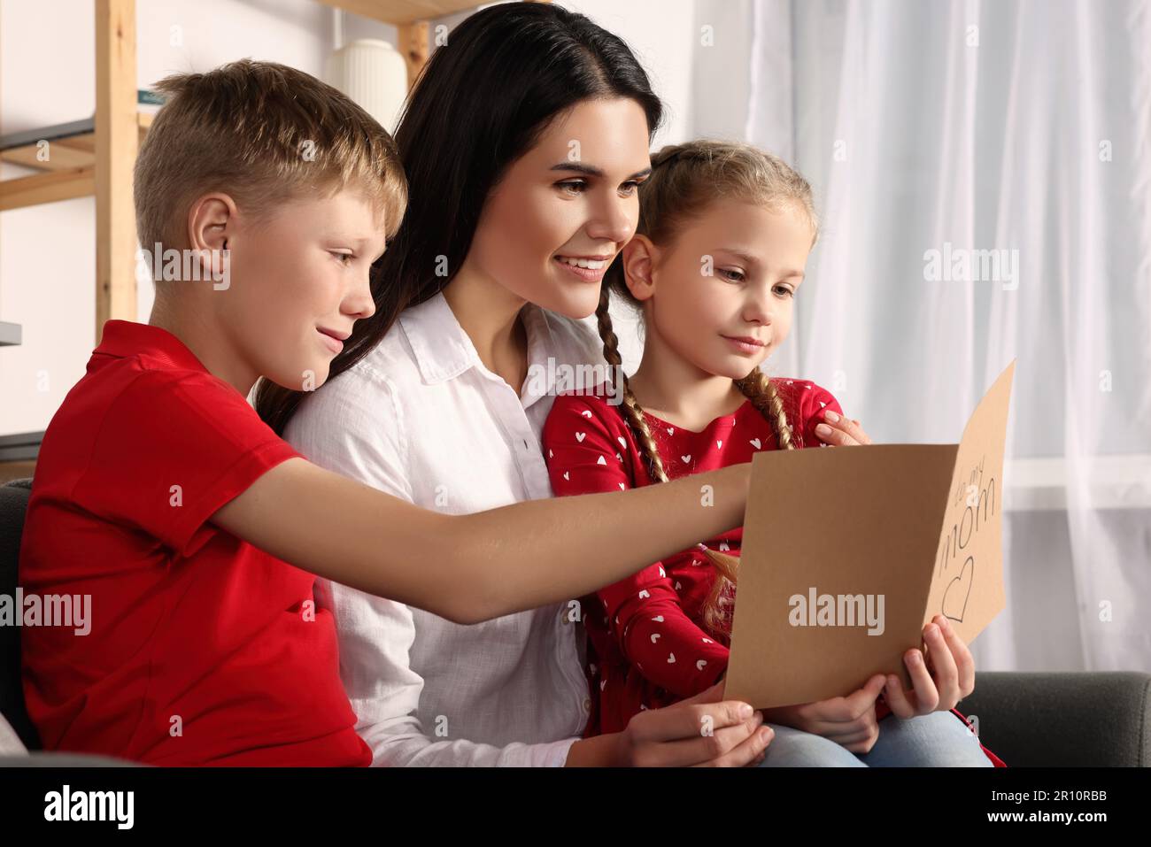 Happy woman receiving greeting card from her children at home Stock ...