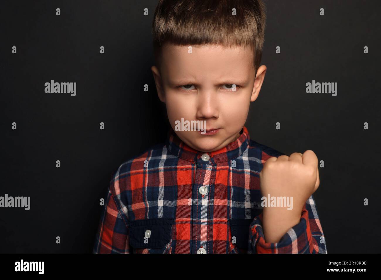 Angry little boy on black background. Aggressive behavior Stock Photo ...