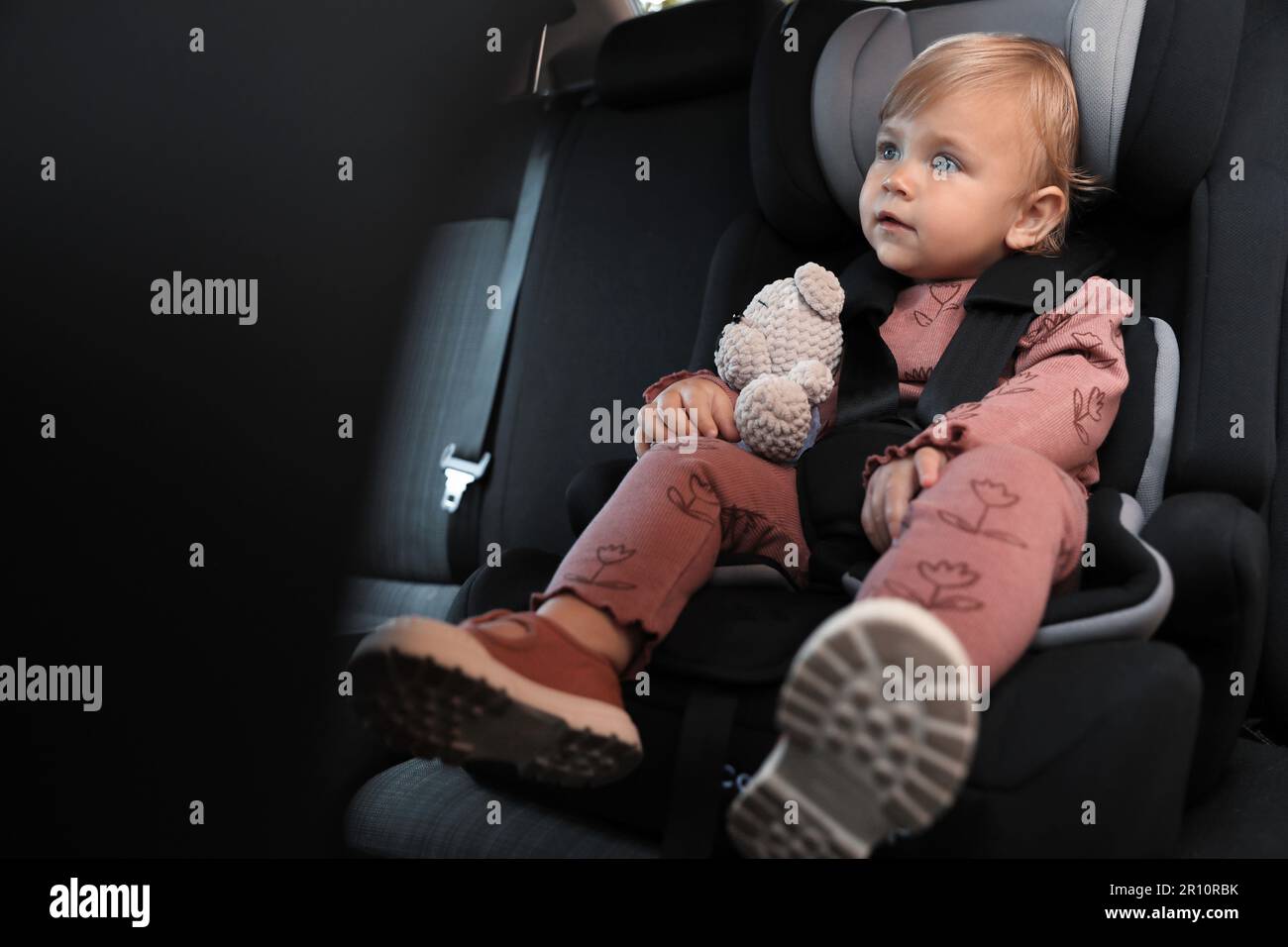 Cute little girl sitting in child safety seat inside car Stock Photo ...