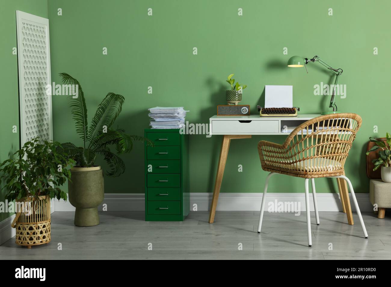 Writer's workplace with typewriter on wooden desk near pale green wall ...