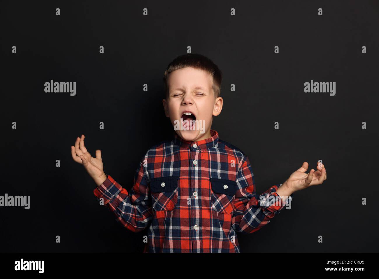 Angry little boy screaming on black background. Aggressive behavior ...