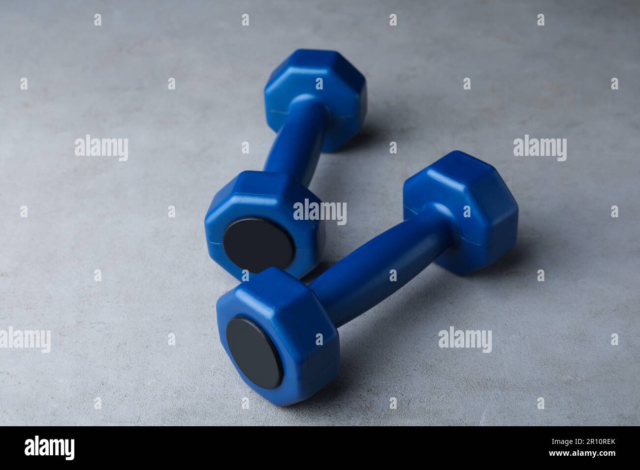 Blue vinyl dumbbells on light grey table Stock Photo - Alamy