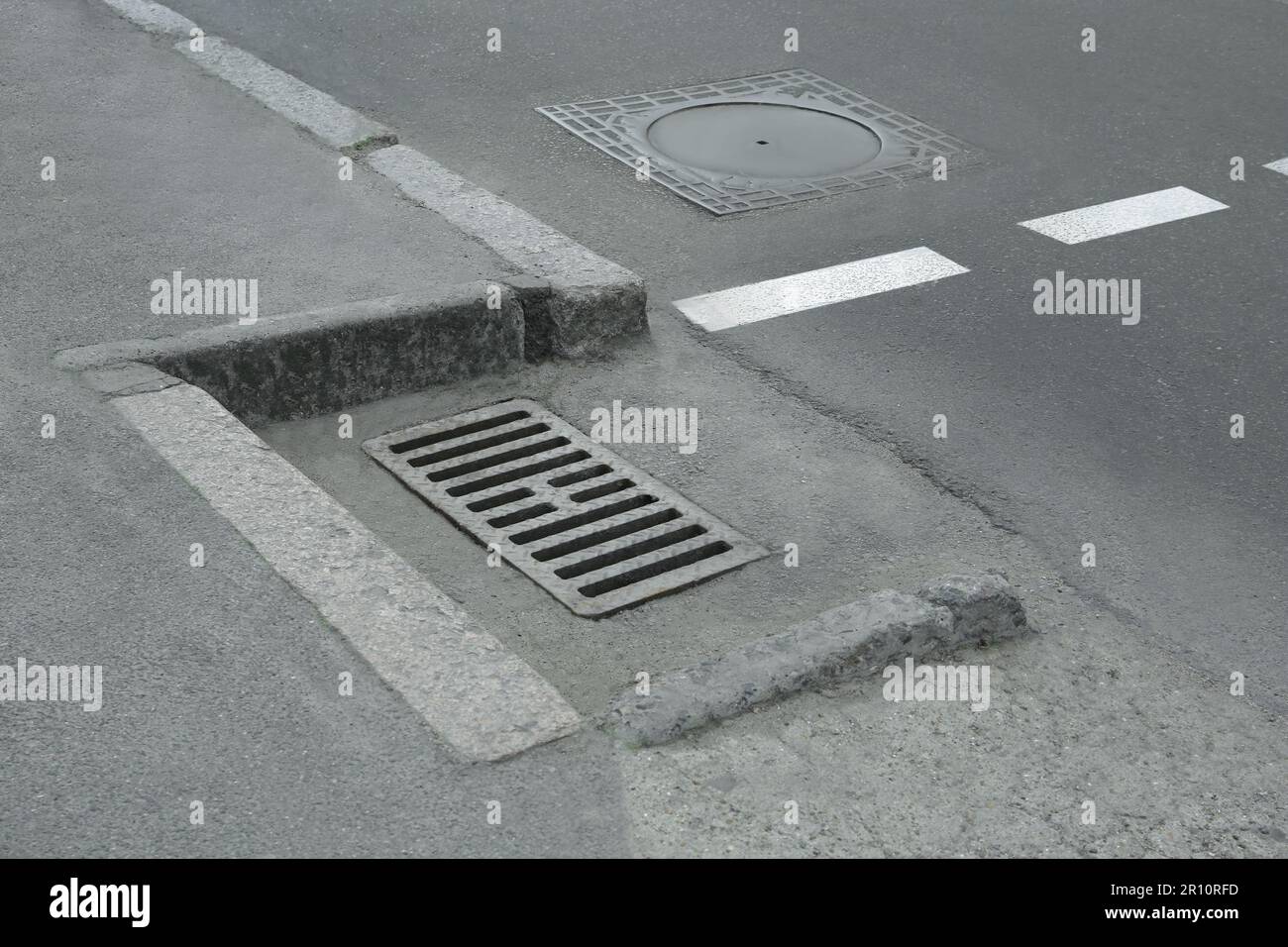 Metal drain grate and sewer hatch on asphalt outdoors Stock Photo - Alamy