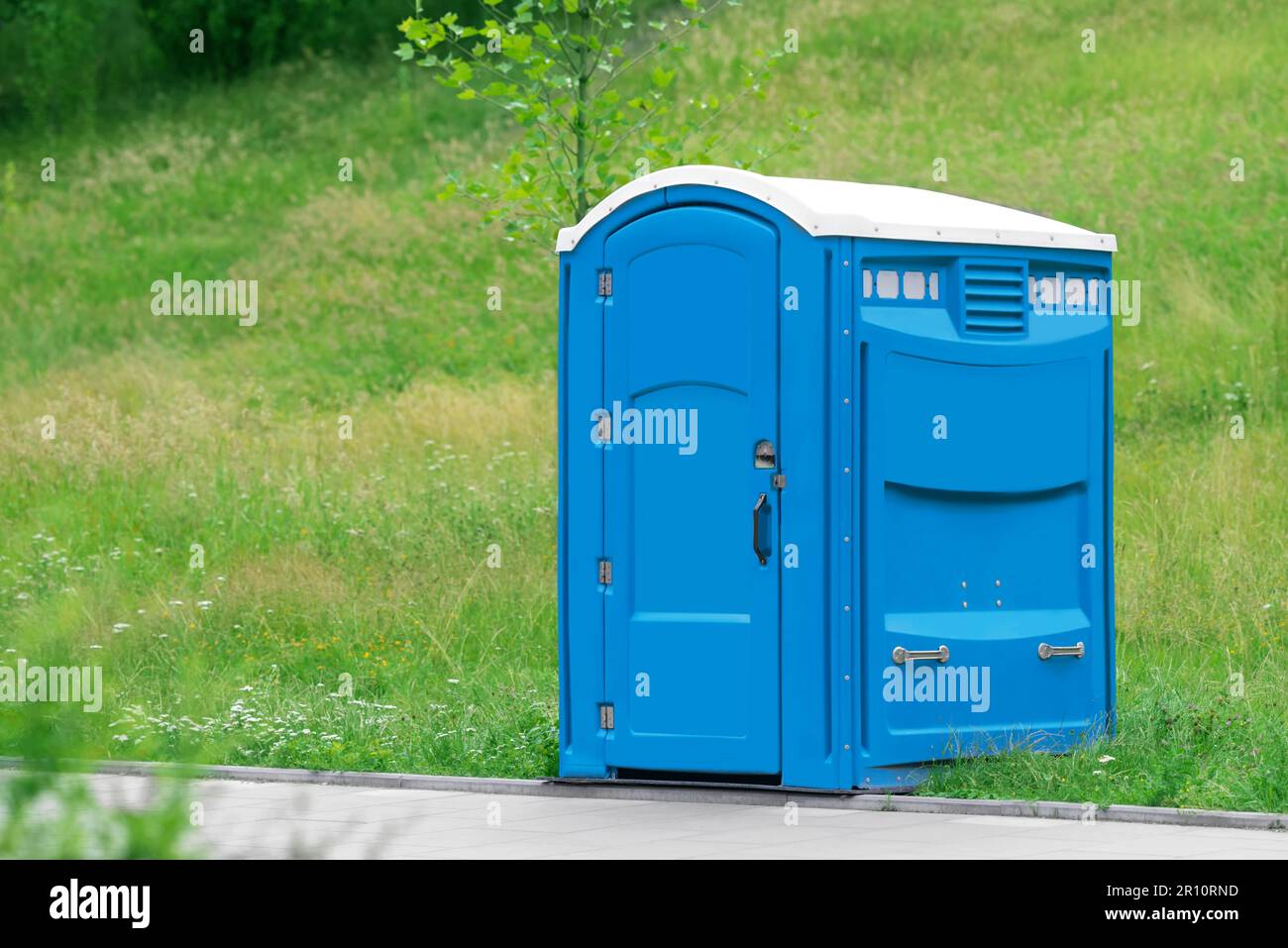 Blue portable toilet near road in green park Stock Photo - Alamy