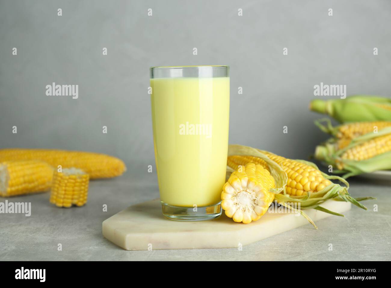 Tasty fresh corn milk in glass and cobs on light grey table Stock Photo ...