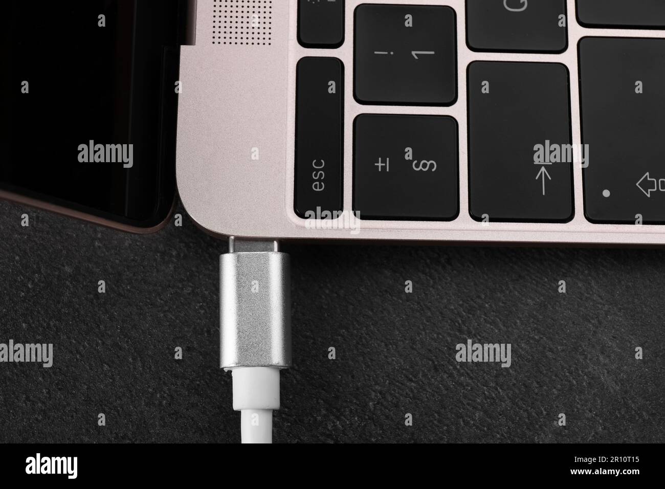 USB cable plugged into laptop port on dark table, top view Stock Photo ...