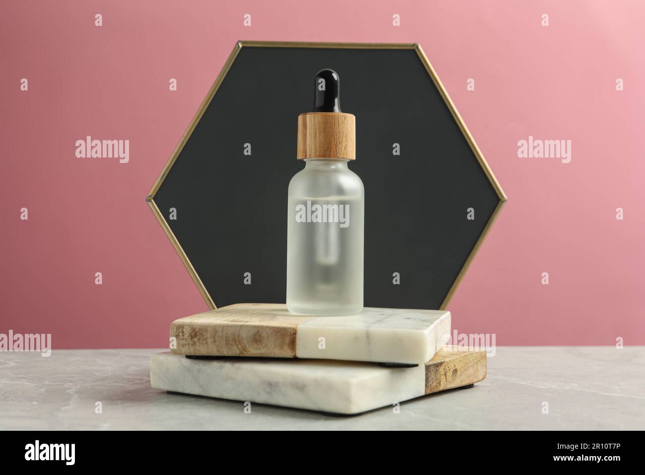 Bottle of face serum with marble boards on grey table against pink ...
