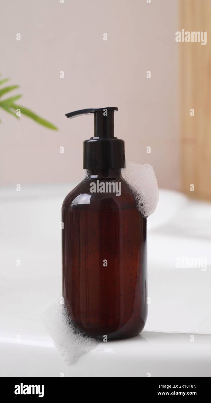 Bottle of bubble bath with foam on tub indoors Stock Photo - Alamy