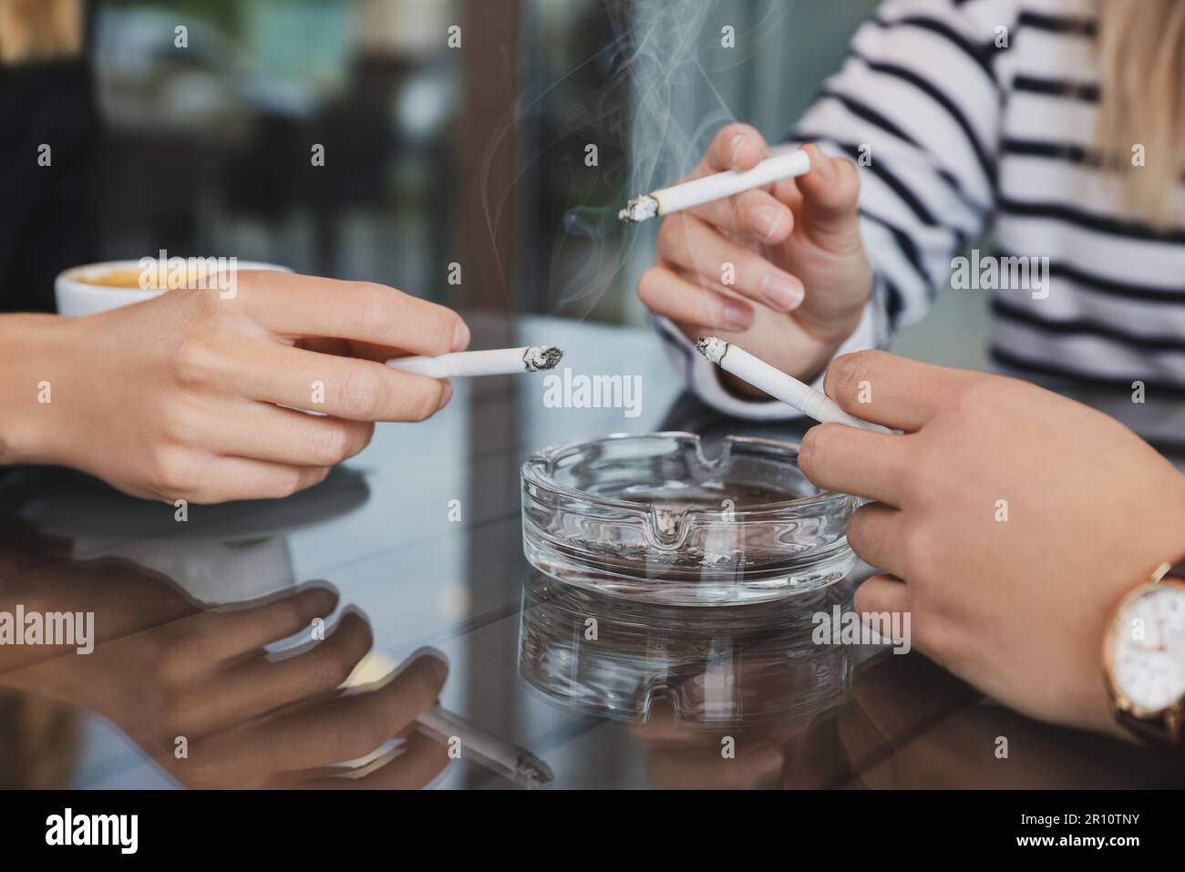 Women holding cigarette over glass ashtray at table, closeup Stock ...