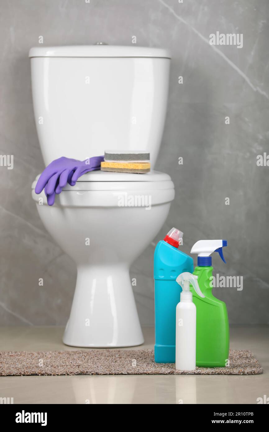 Different cleaning supplies and toilet bowl in bathroom Stock Photo - Alamy
