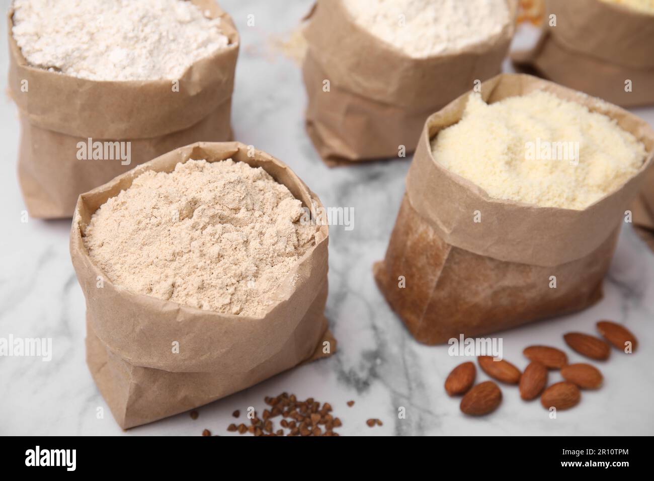 Paper bags with different types of flour and ingredients on white ...