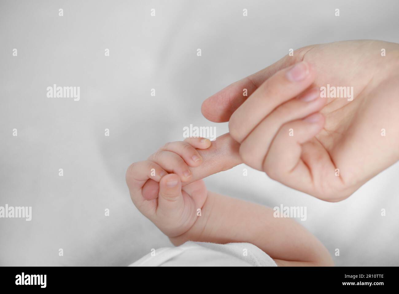 Baby holding mother?s hand on bed, closeup Stock Photo - Alamy