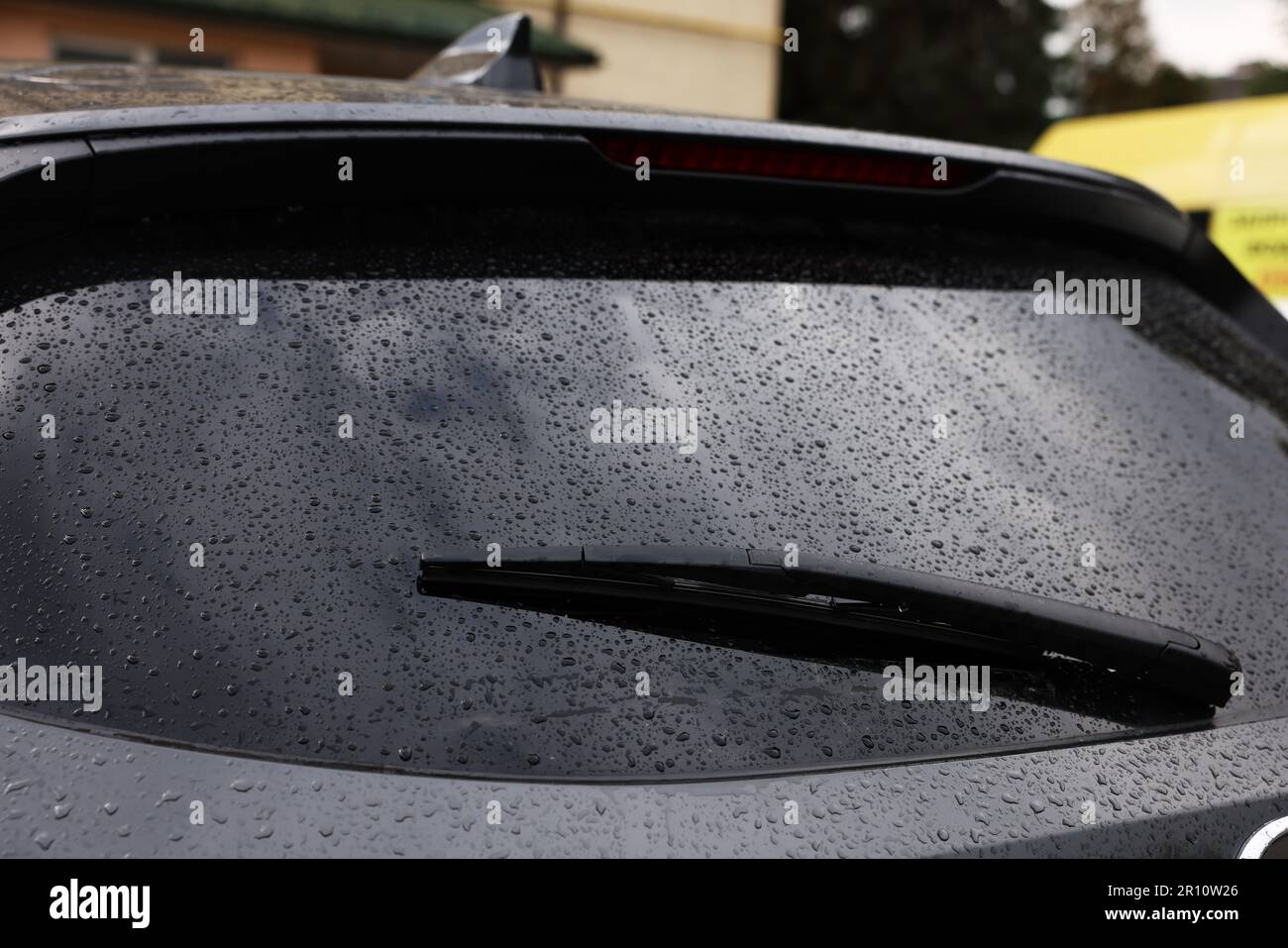 Car wiper cleaning water drops from rear windshield glass outdoors ...