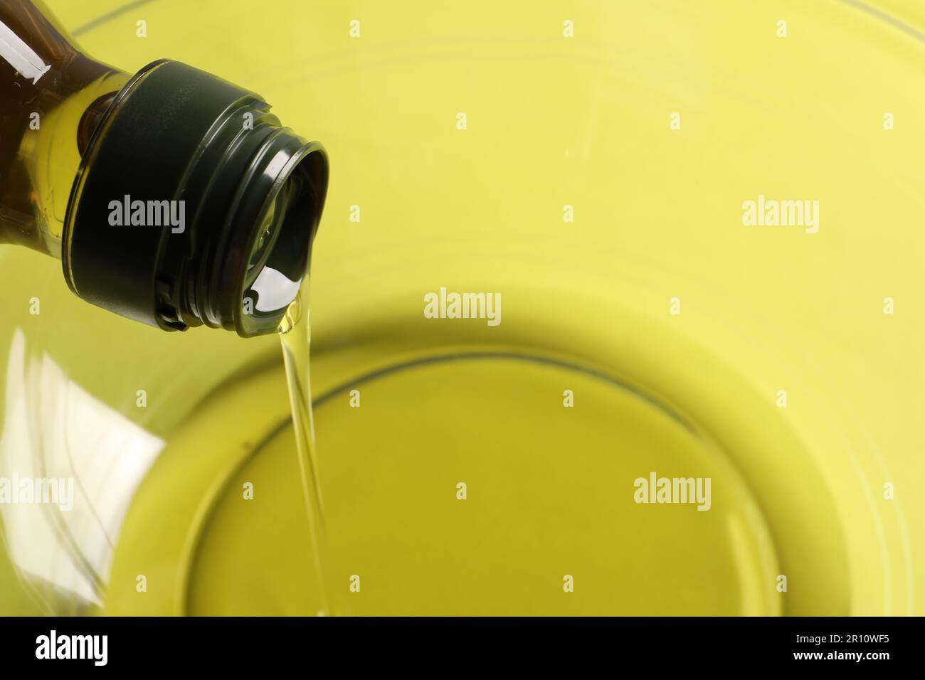 Pouring cooking oil from bottle into bowl, closeup Stock Photo - Alamy