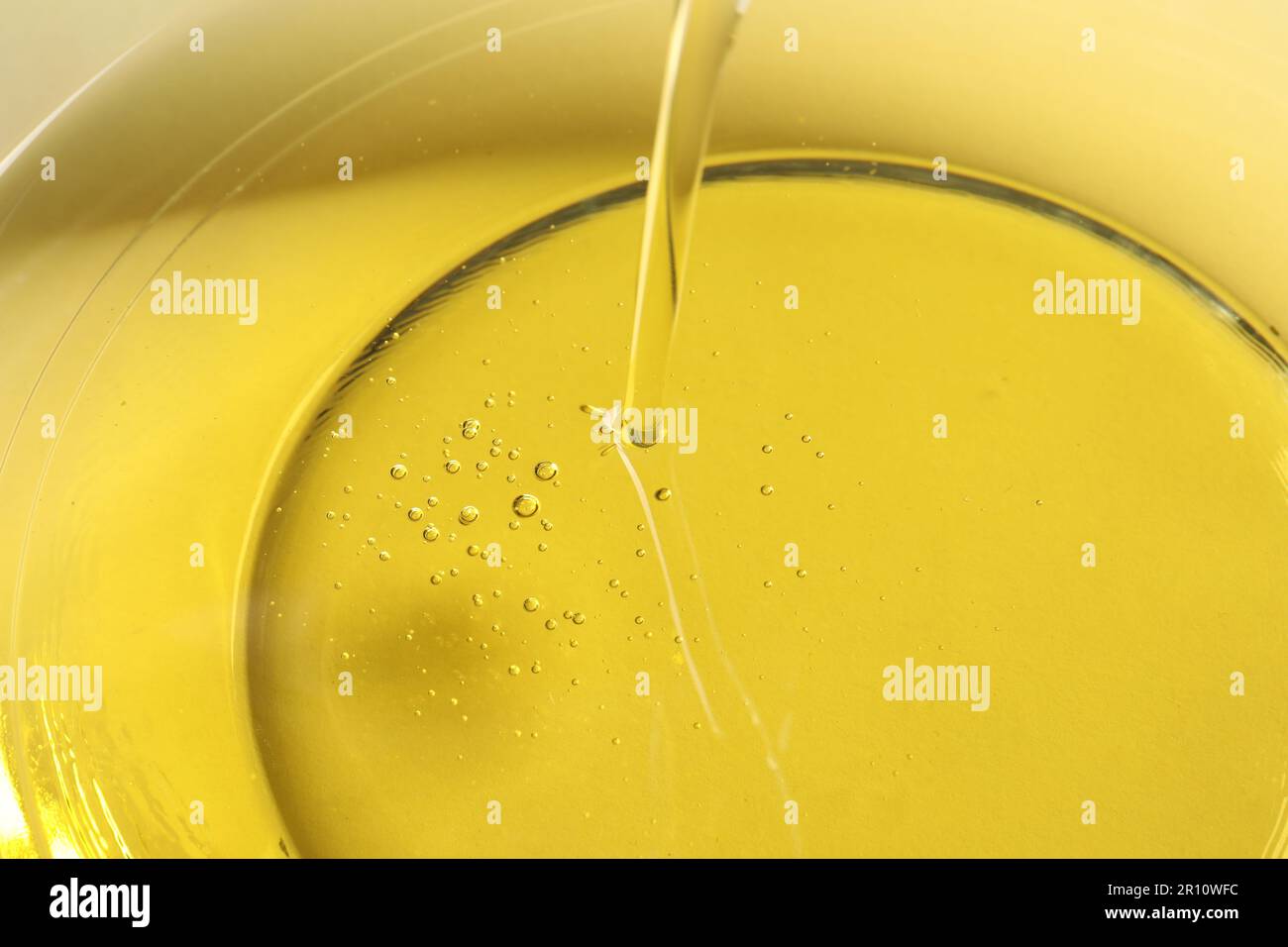 Pouring cooking oil into glass bowl, closeup Stock Photo - Alamy