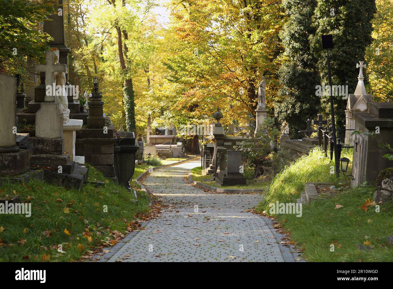 View of cemetery with granite tombstones and paved footpath on sunny ...