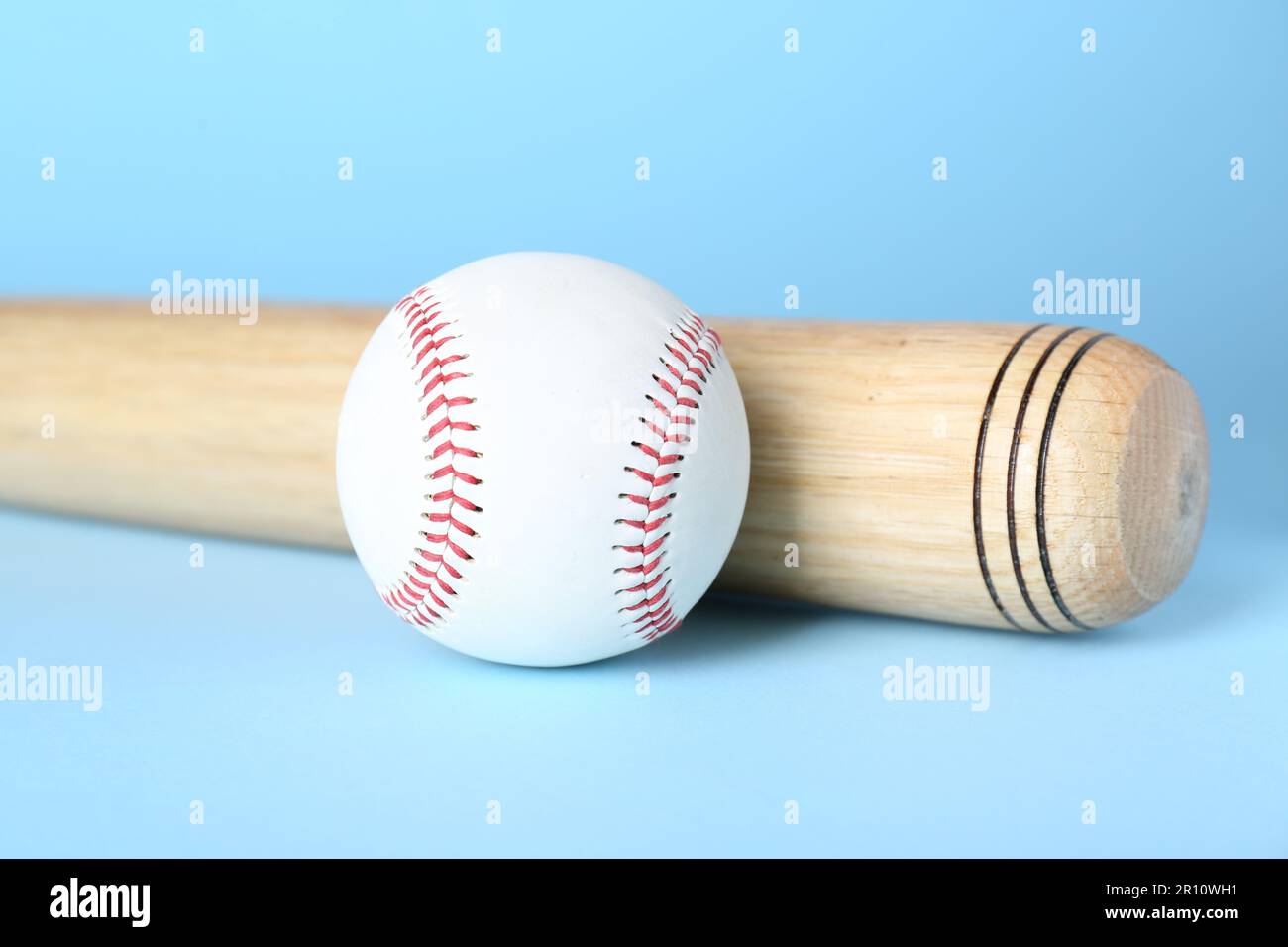 Wooden baseball bat and ball on light blue background, closeup. Sports ...