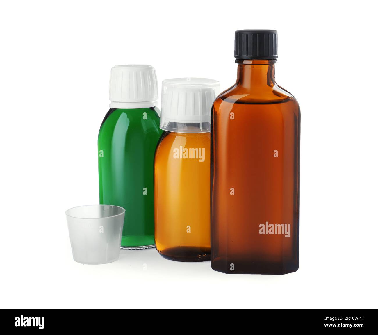 Bottles of syrups with measuring cups on white background. Cough and ...
