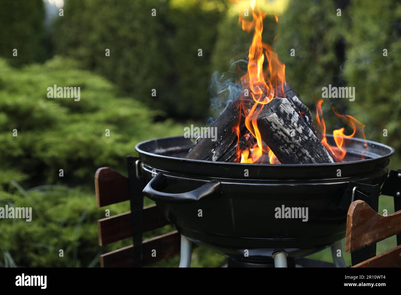 Portable barbecue grill with fire flames outdoors, closeup. Space for ...