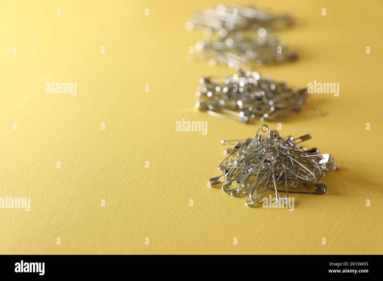 Piles of safety pins on yellow background, space for text Stock Photo ...