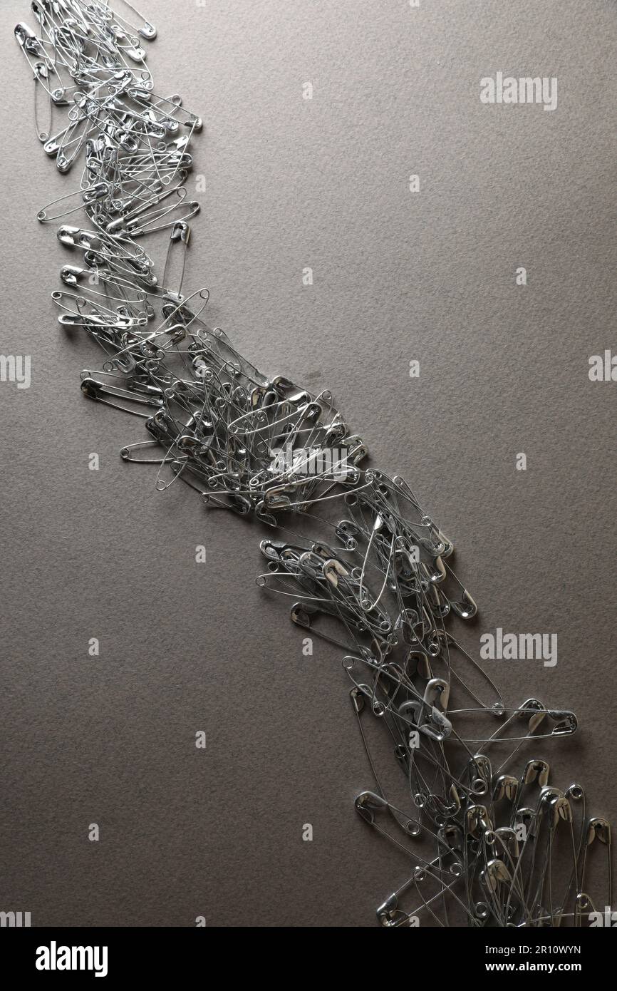Many safety pins on light grey textured background Stock Photo - Alamy