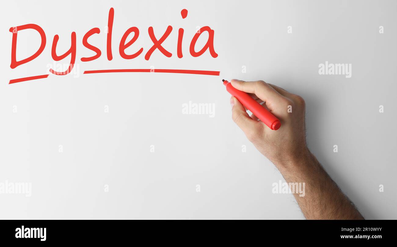 Man writing word Dyslexia on white background, closeup. Banner design ...