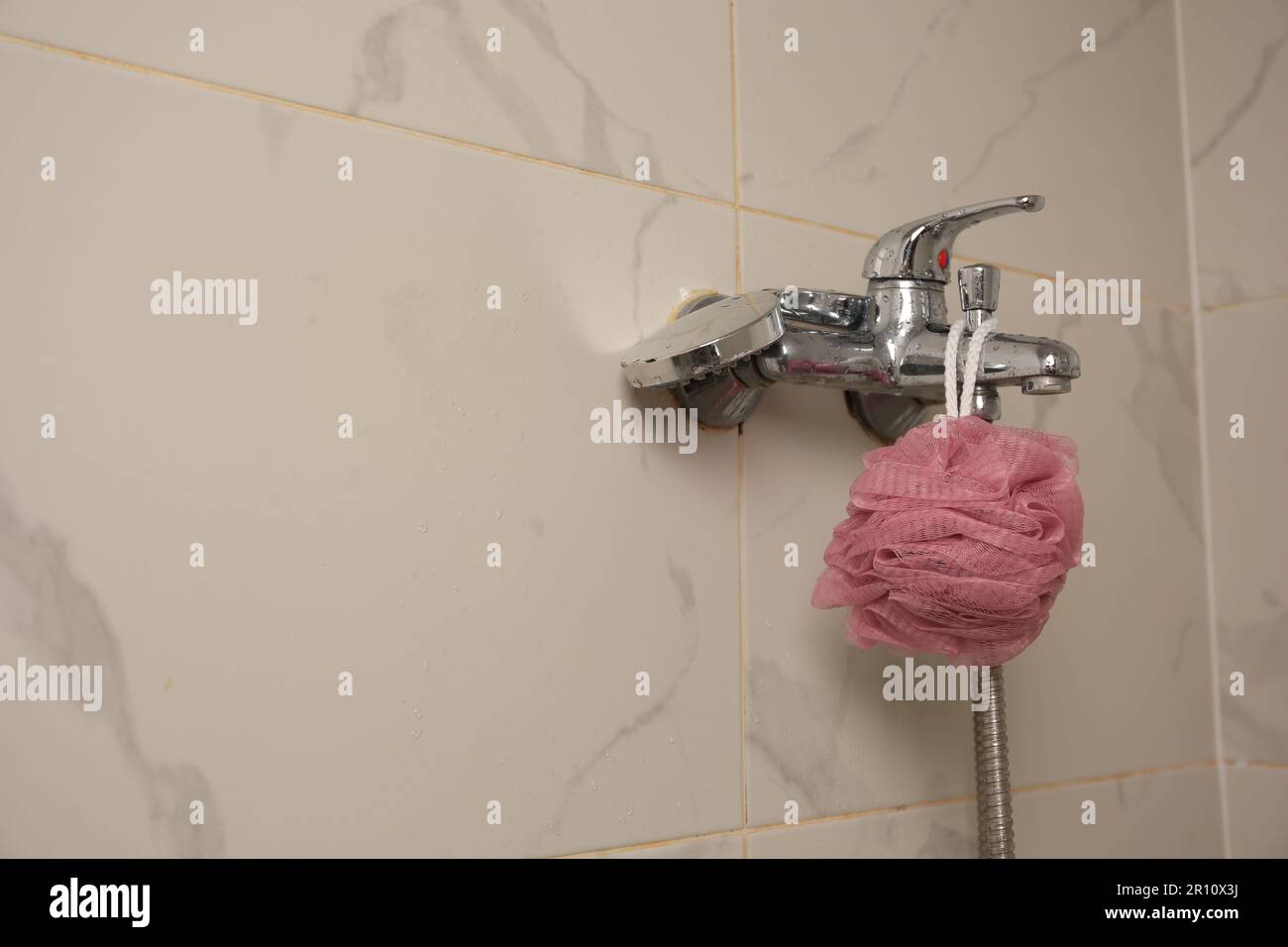 Pink shower puff hanging on faucet in bathroom, space for text Stock ...