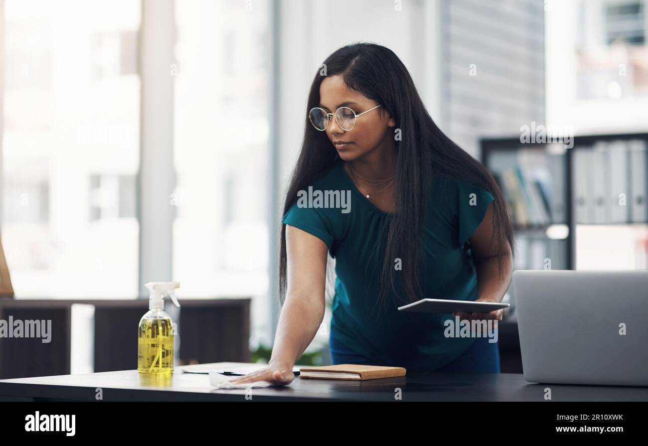 Keeping things sanitary around her workspace. a young businesswoman ...