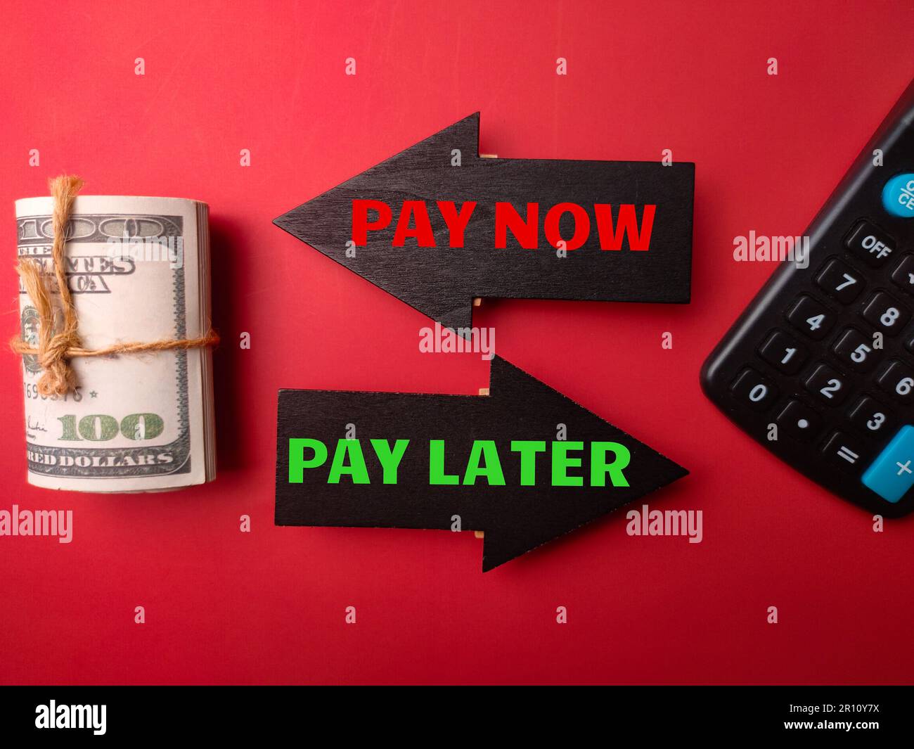 Banknotes and calculator with word PAY NOW PAY LATER on a red ...