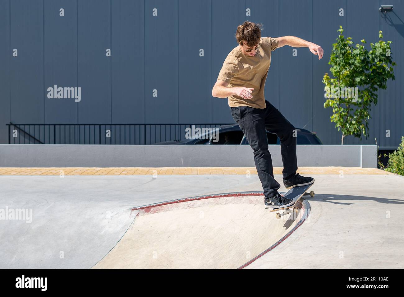 Skateboarder doing frontside five-o grind trick in concrete skatepark ...