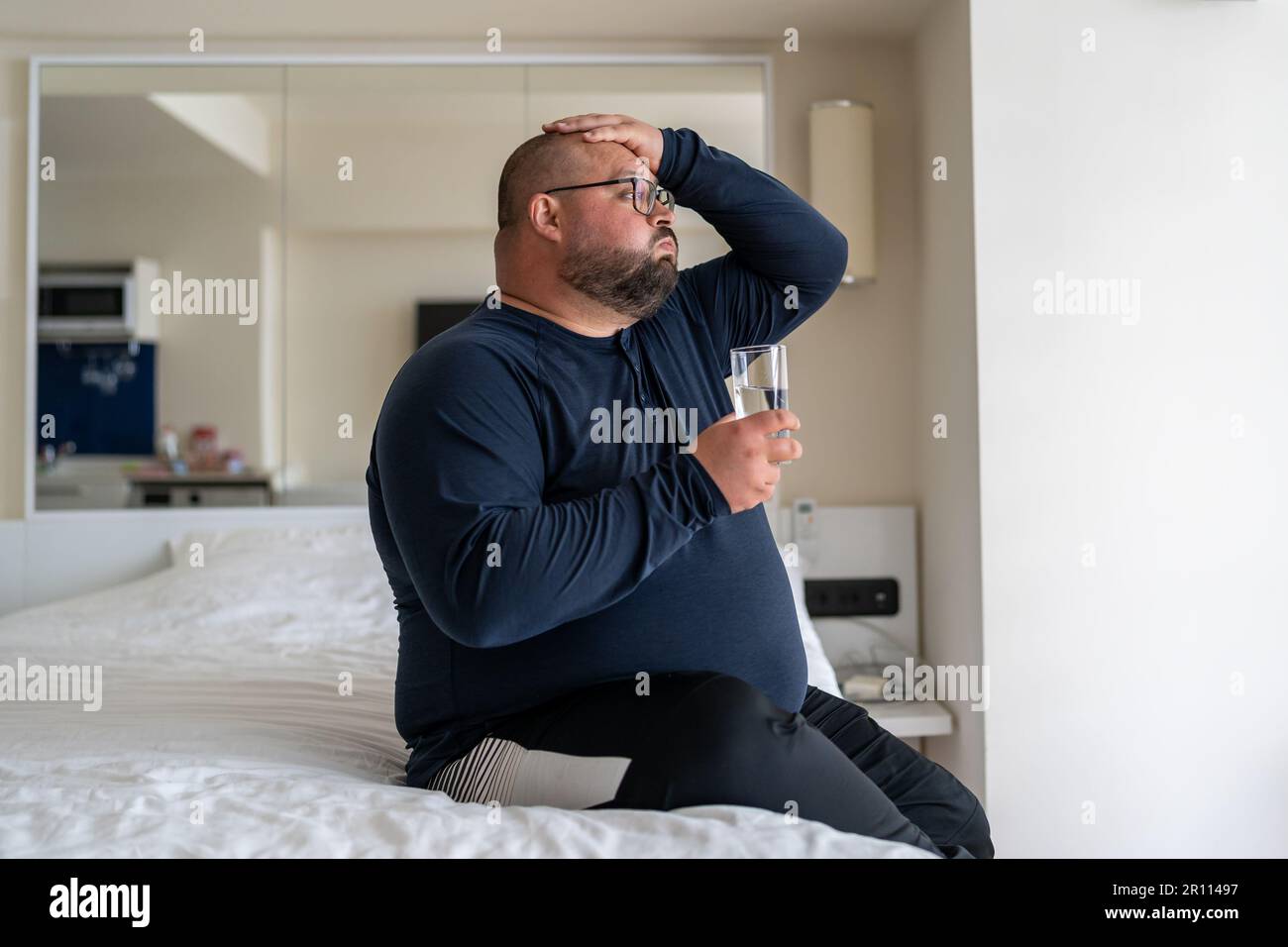 Sad overweight bearded man suffering from strong headache or migraine ...