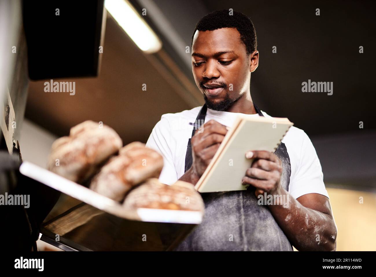 Another order, done and dusted. a male baker making notes while working ...