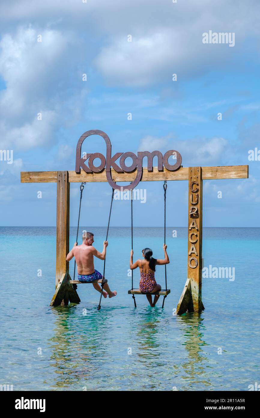 Couple of men and women at a swing in the ocean of Curacao Caribbean ...