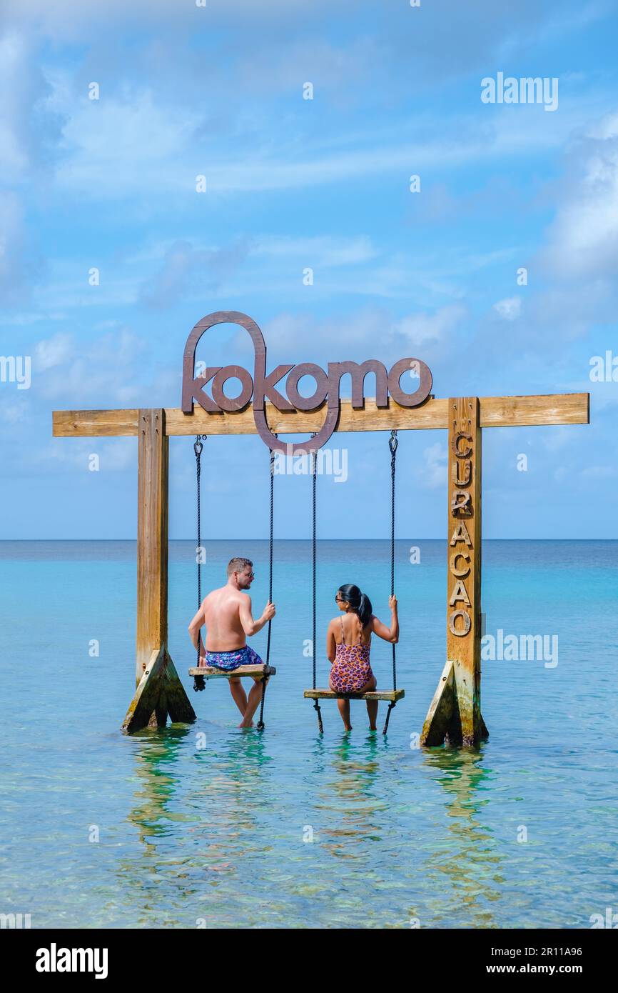 Couple of men and women at a swing in the ocean of Curacao Caribbean ...