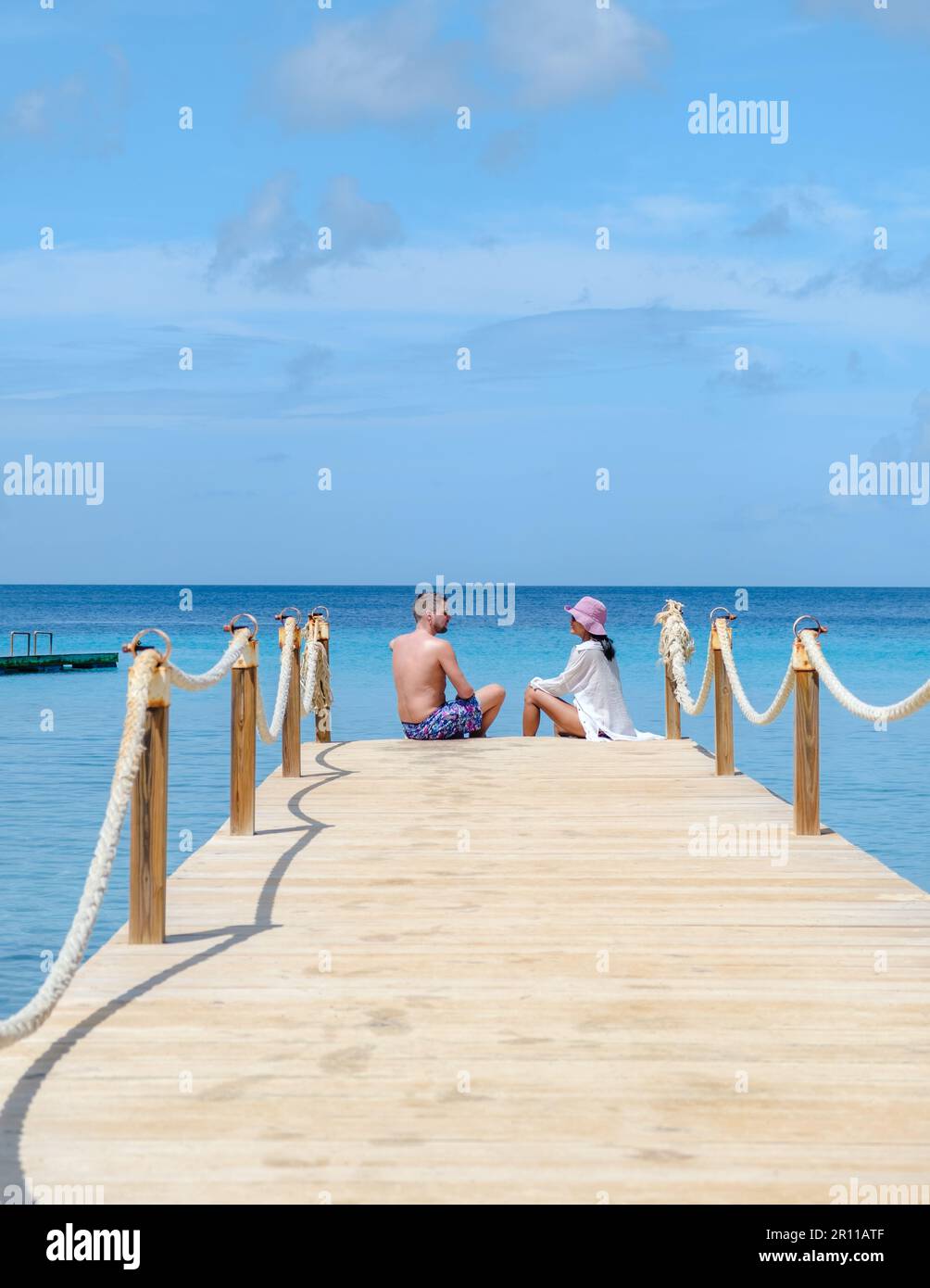 Couple of men and women at a wooden pier in the ocean of Curacao ...