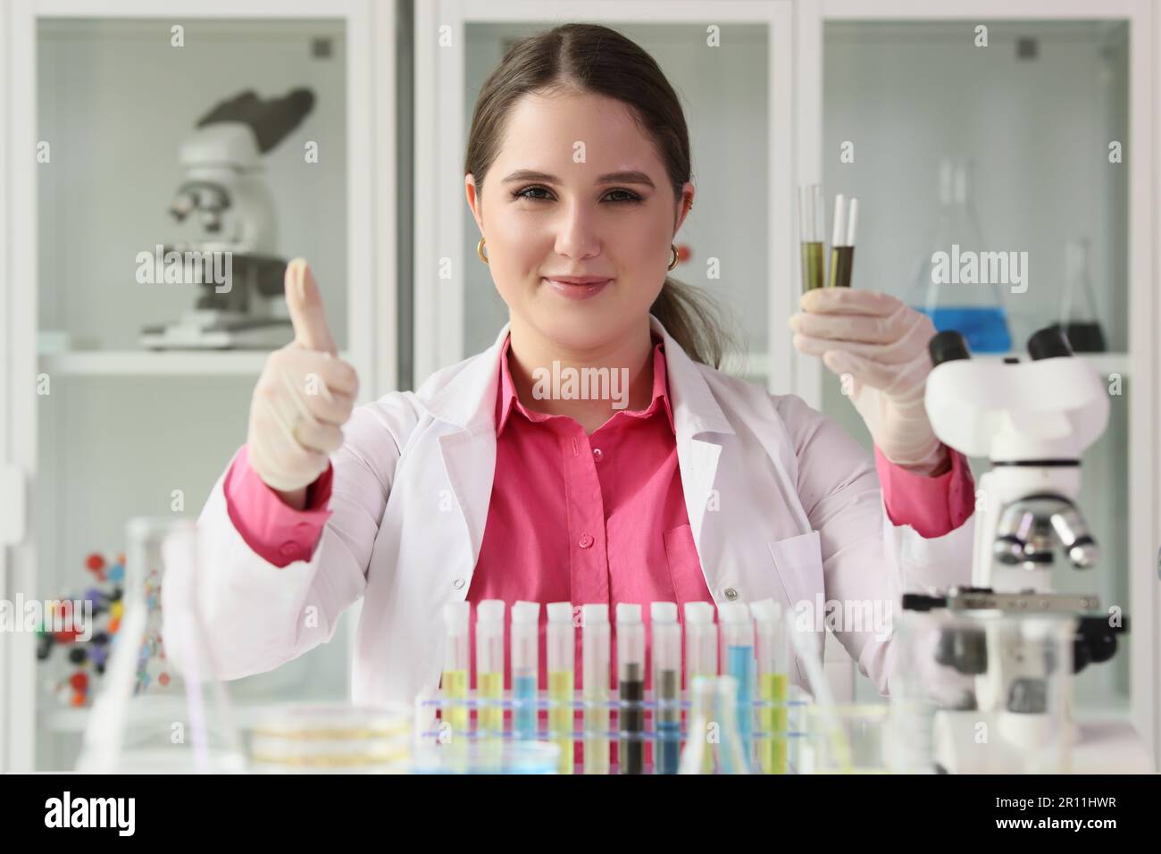 Woman chemist holding test tubes and showing thumbs up sign Stock Photo ...