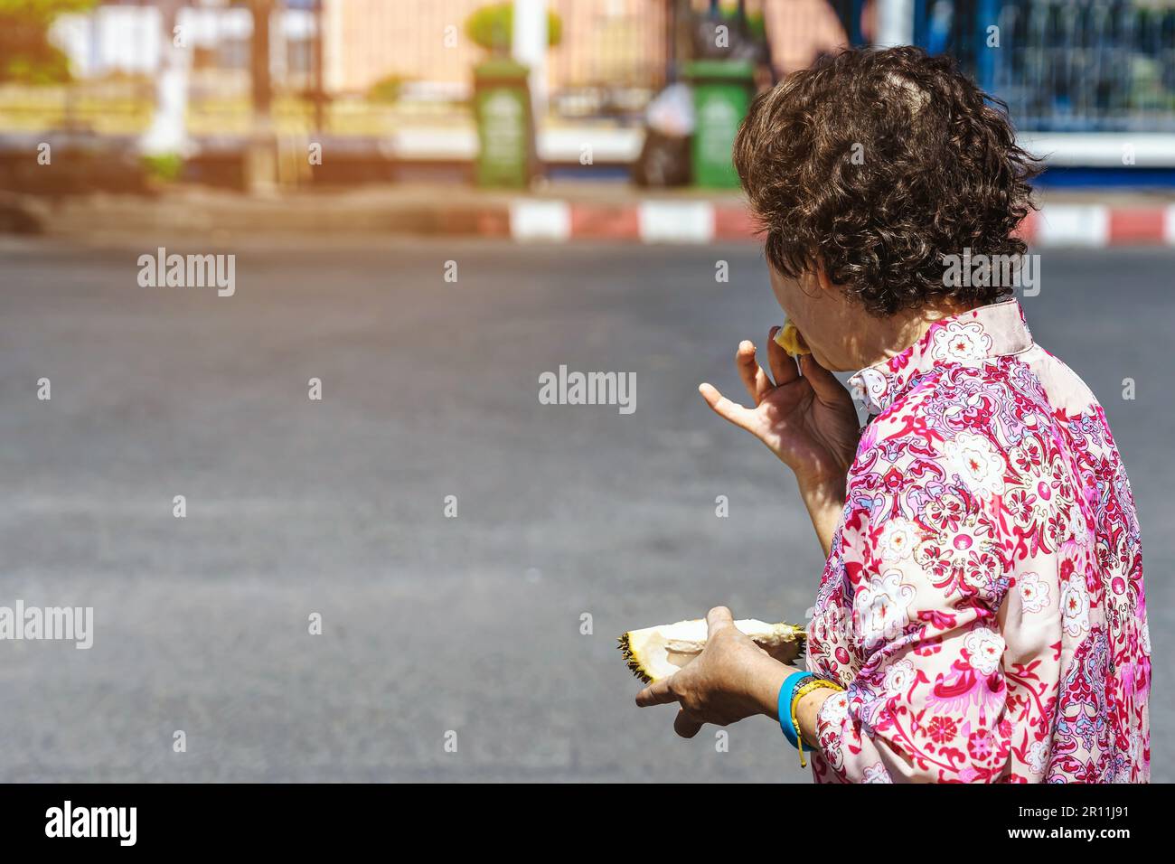 Back view portrait of Asian elderly woman happy eating sweet durian ...