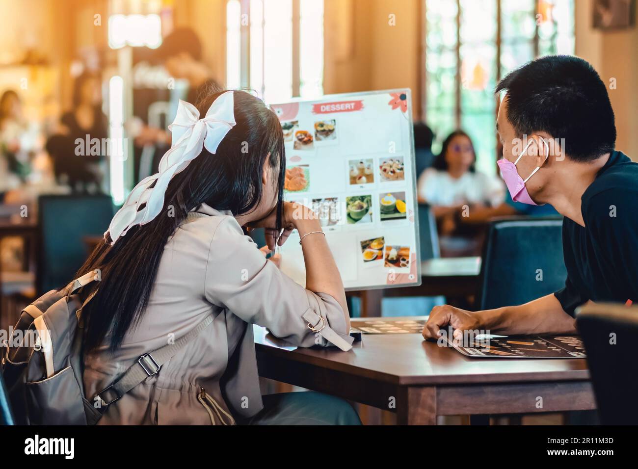 Back view of Asian young couple reading menu and choosing meal together ...