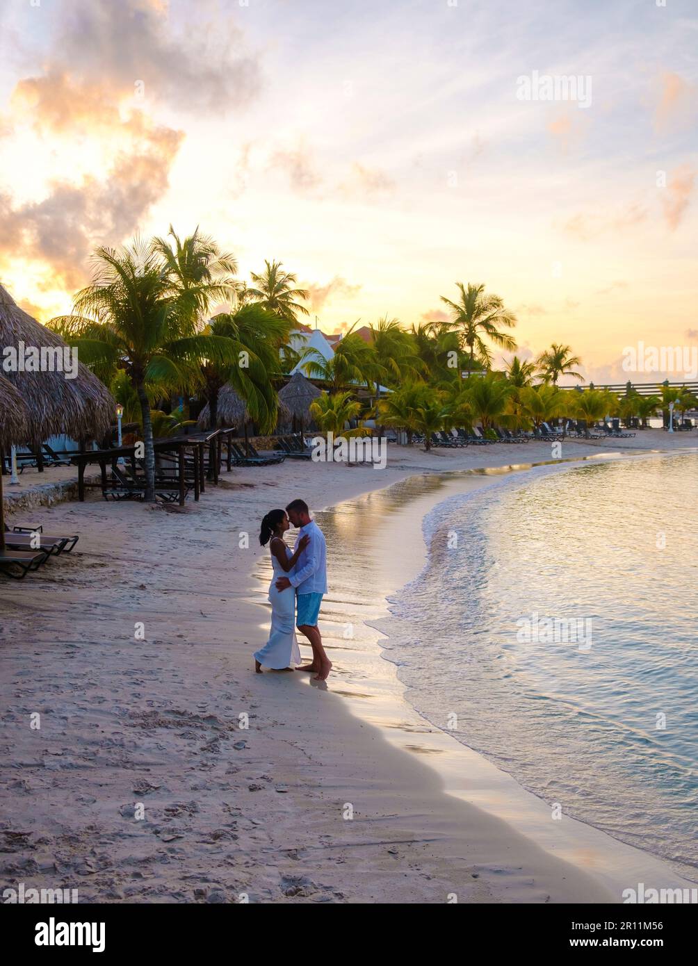 Couple on the beach of Curacao during sunset, men and women watching ...