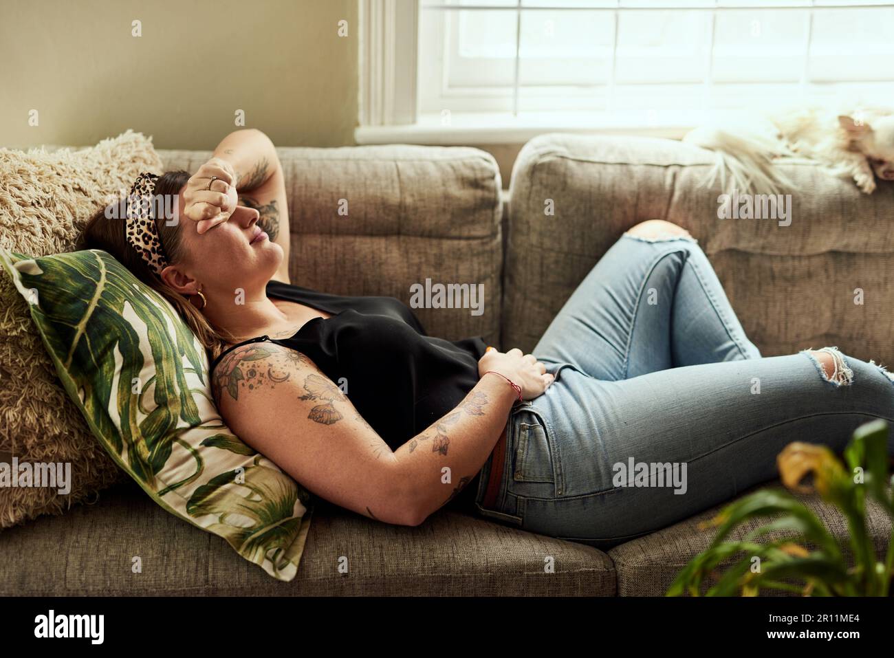 Period pain, menstruation and a woman on a sofa in the living room of ...