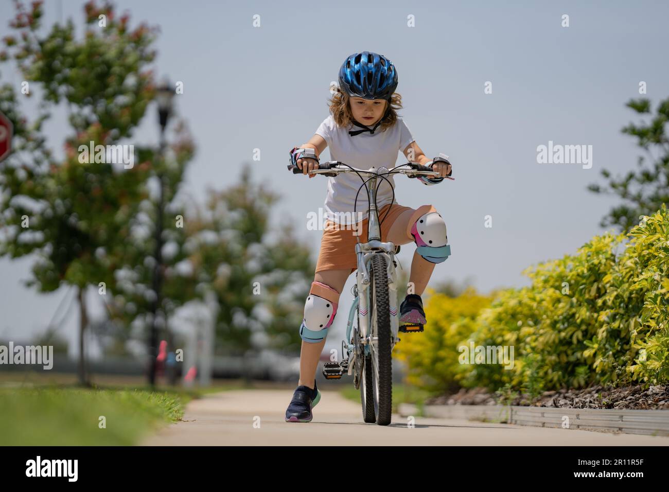 Little kid riding a bike in summer park. Children learning to drive a ...