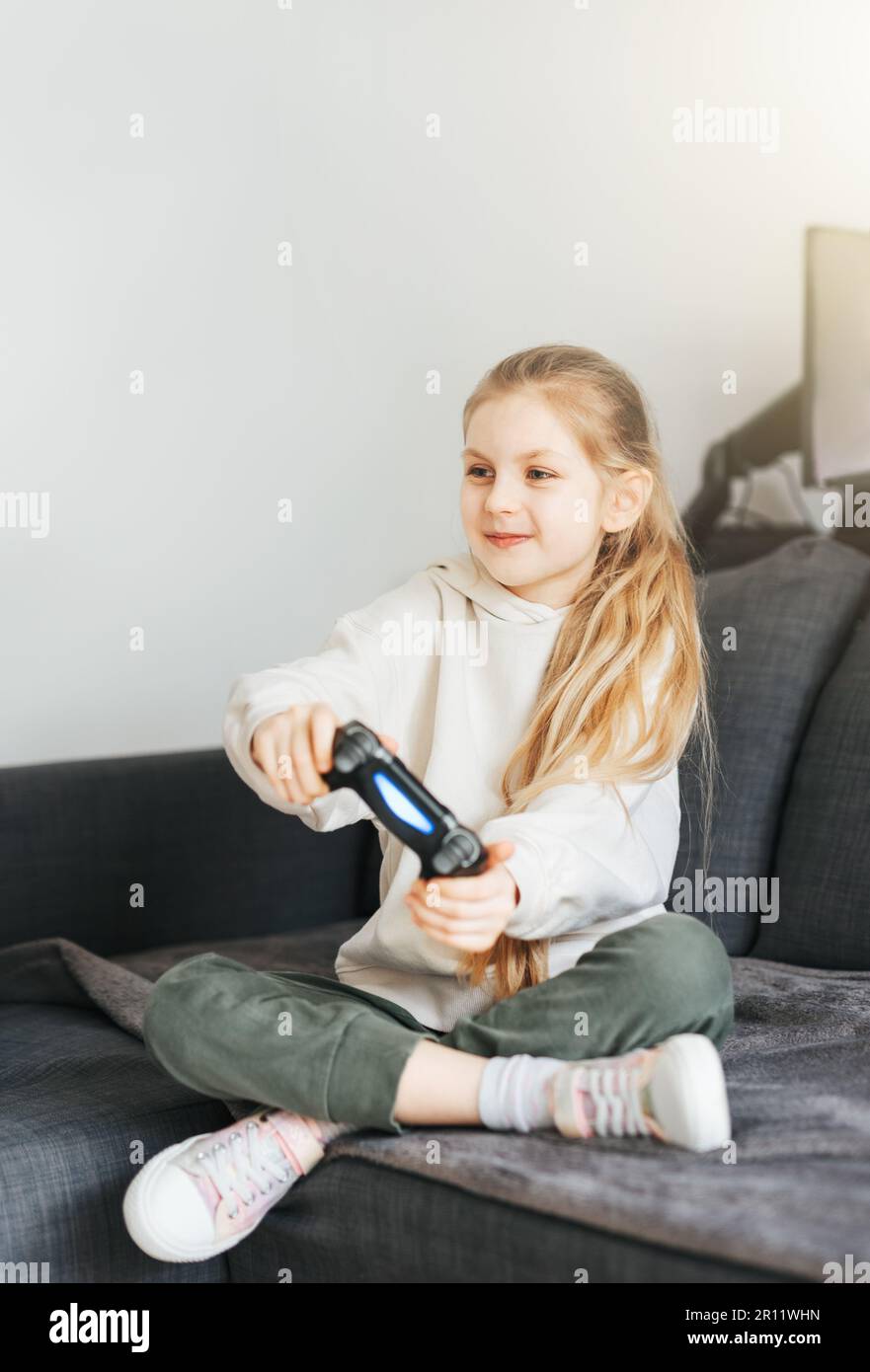 A little girl holding game controller playing video games Stock Photo ...