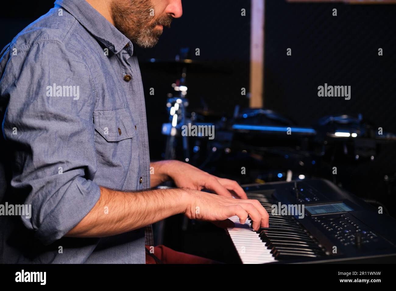 Musician man playing keyboard synthesizer piano in a recording studio ...