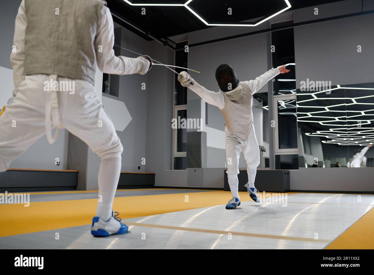 Athletes in uniforms and protective helmet mask fighting duel with ...