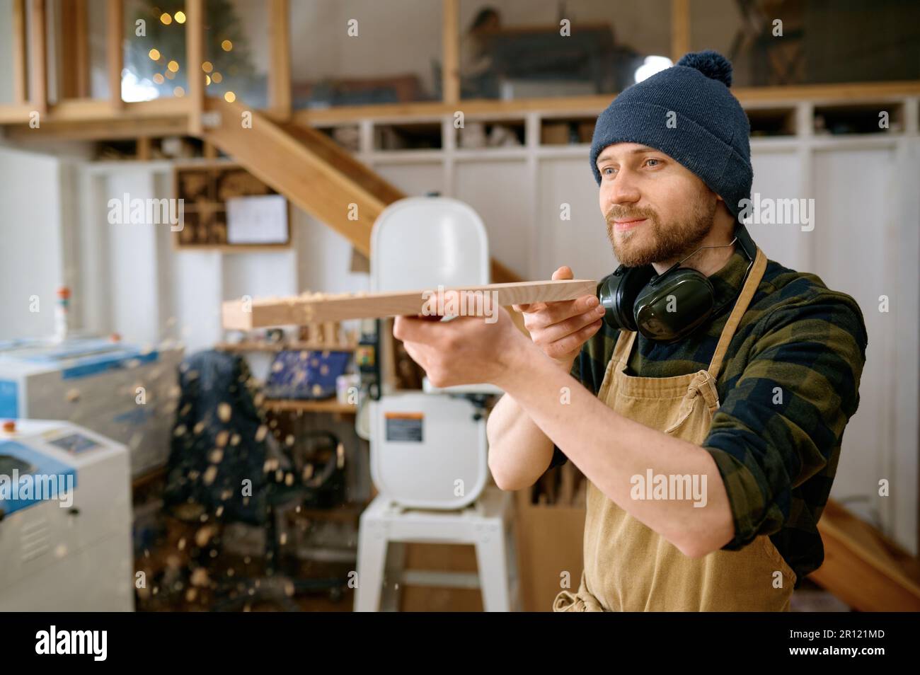 Young man carpenter blowing sawdust from board wooden plank Stock Photo ...