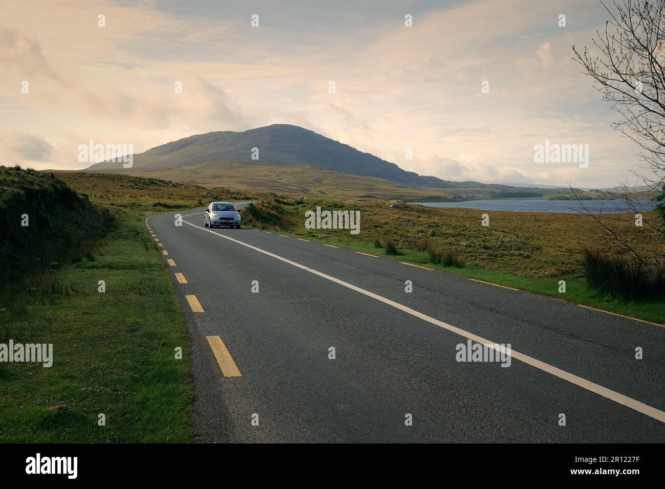 Car driving on empty scenic road trough nature by the lough inagh with ...