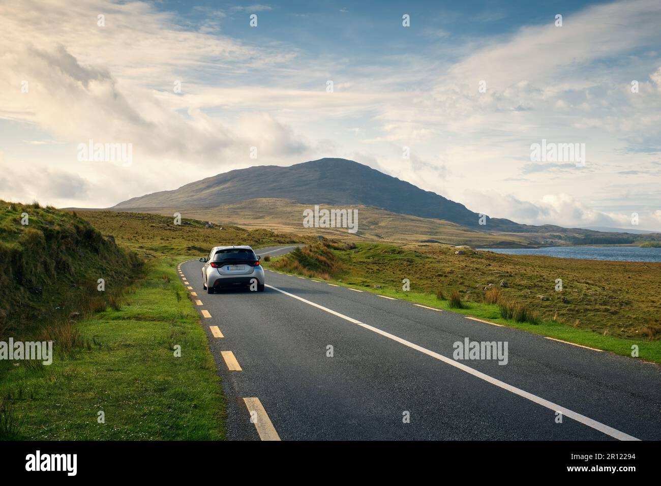Car driving on empty scenic road trough nature by the lough inagh with ...