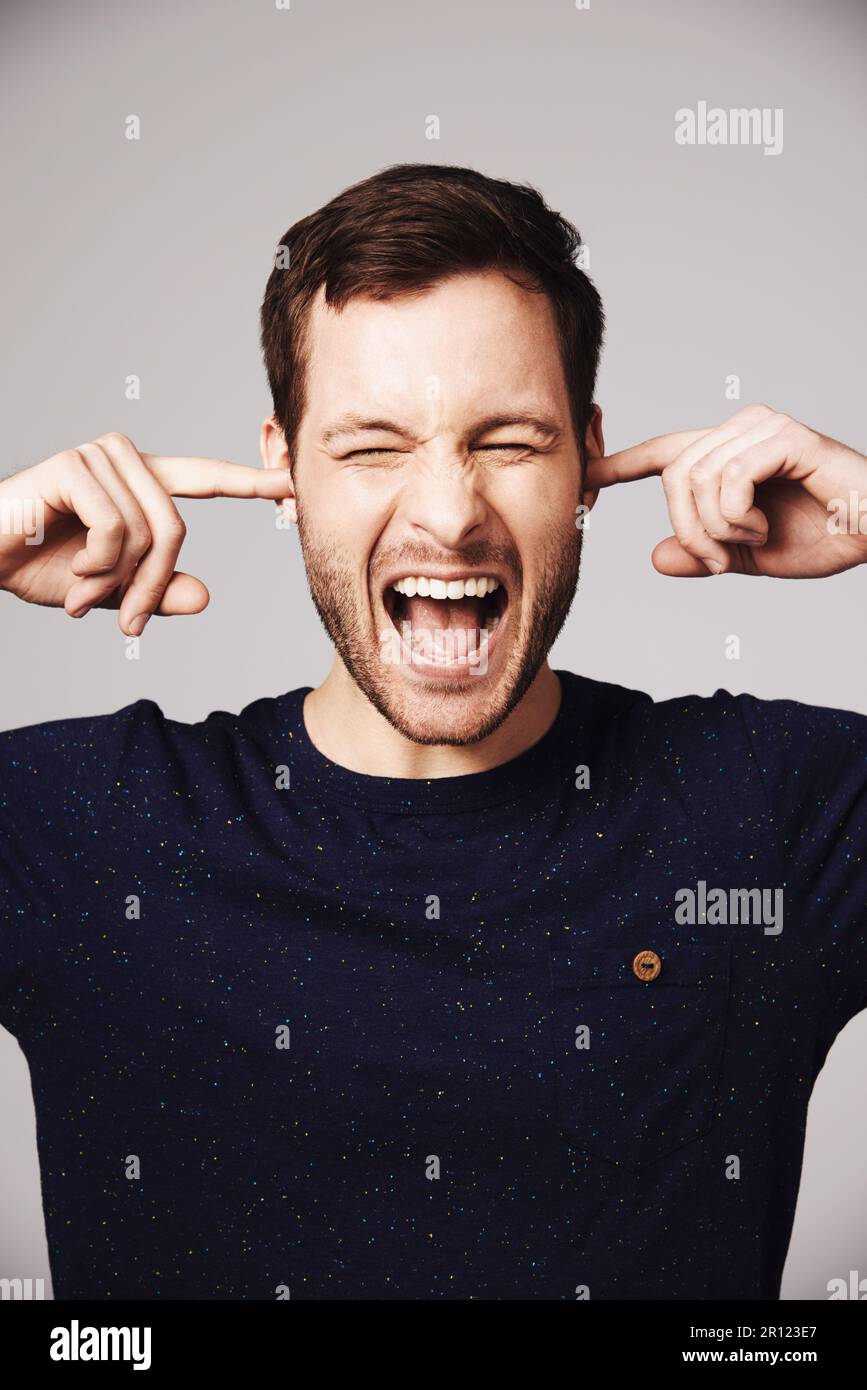 Man, scream and block ears in studio with anger, frustrated face and ...